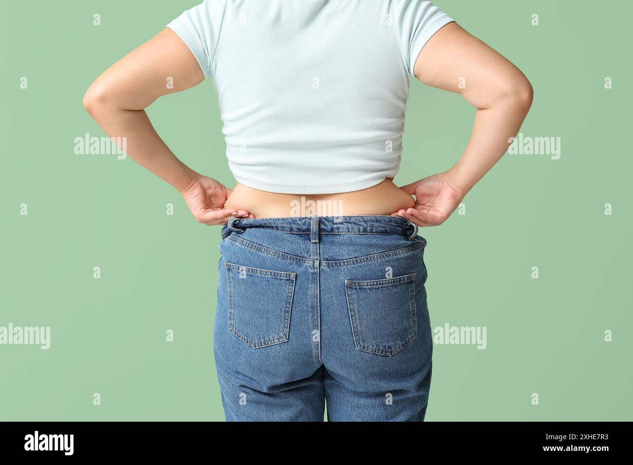 Overweight Woman In Tight Jeans On Green Background Back View Excess