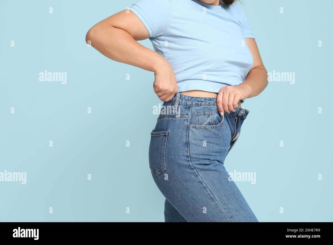 Overweight woman in tight jeans on blue background. Excess weight ...