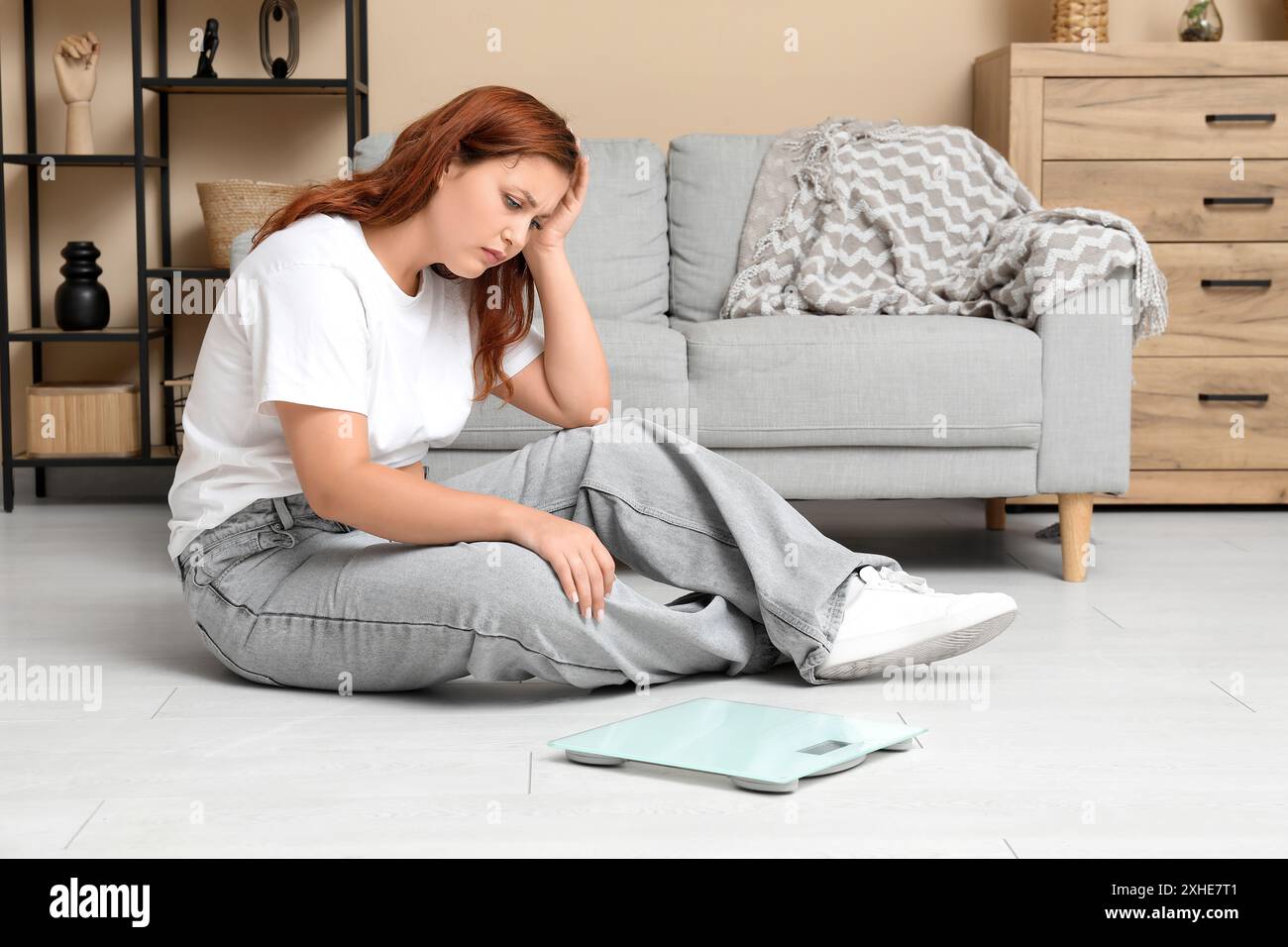Troubled overweight woman in tight jeans with scales at home. Excess ...