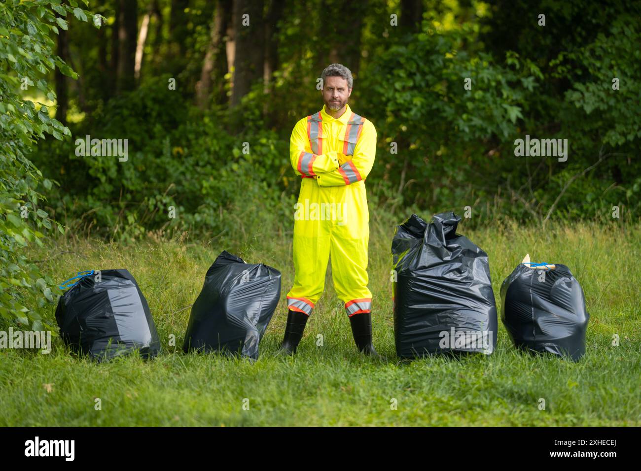Environment plastic pollution. Volunteer collecting trash in the forest and holding a garbage ...