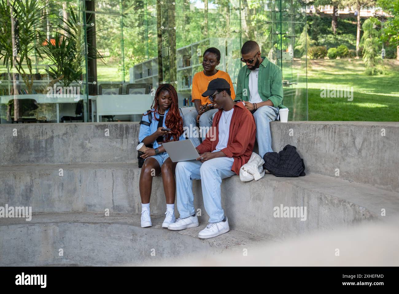 Company of happy black students studying together sitting on staircase ...