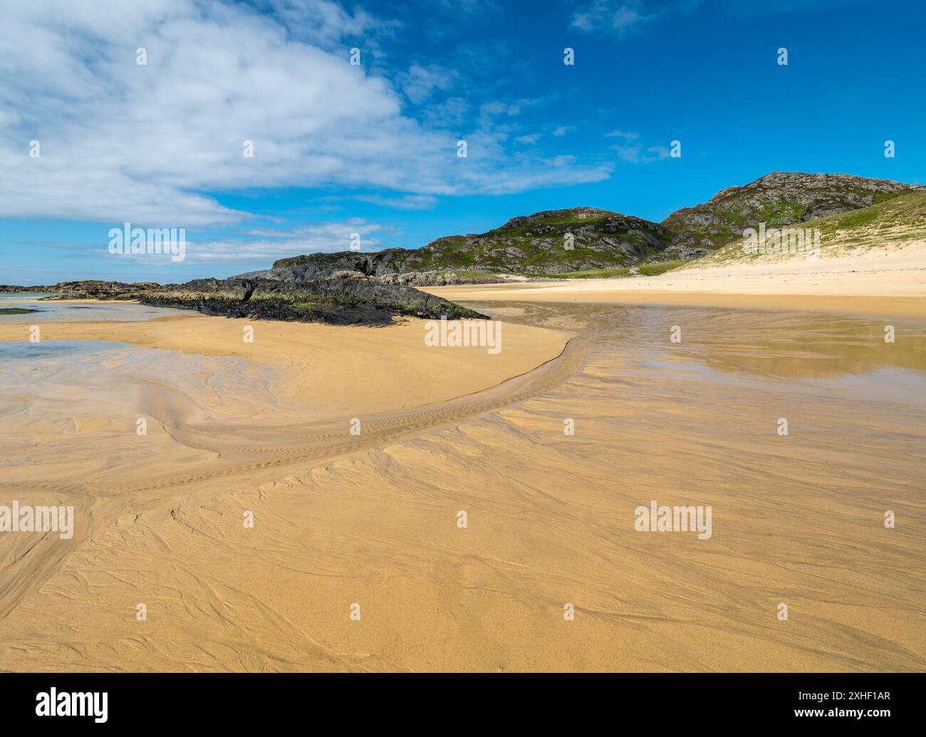 Pretty rivulet patterns in the yellow sand of Kiloran beach with blue ...