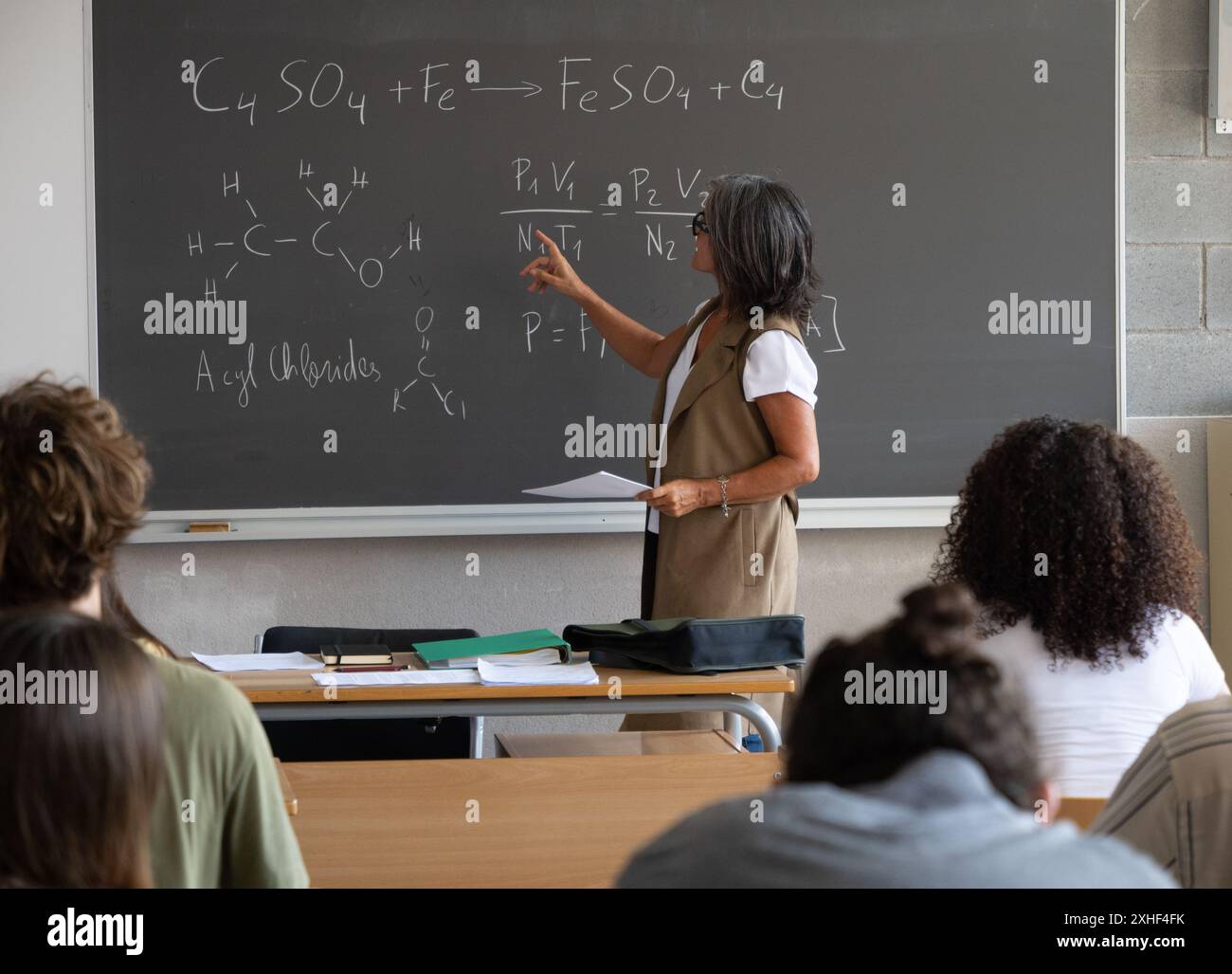 Woman teacher giving a science class explaining at the blackboard in a ...