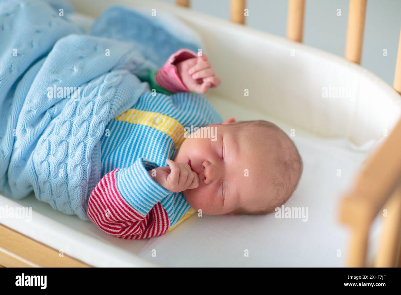 Newborn baby in hospital room. New born child in wooden co-sleeper crib ...
