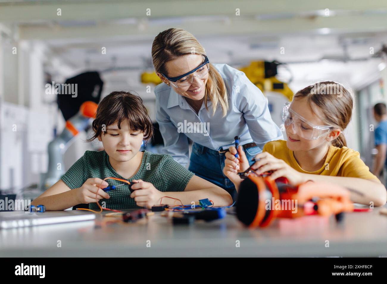 Female teacher helping to girls working on small robot, building ...