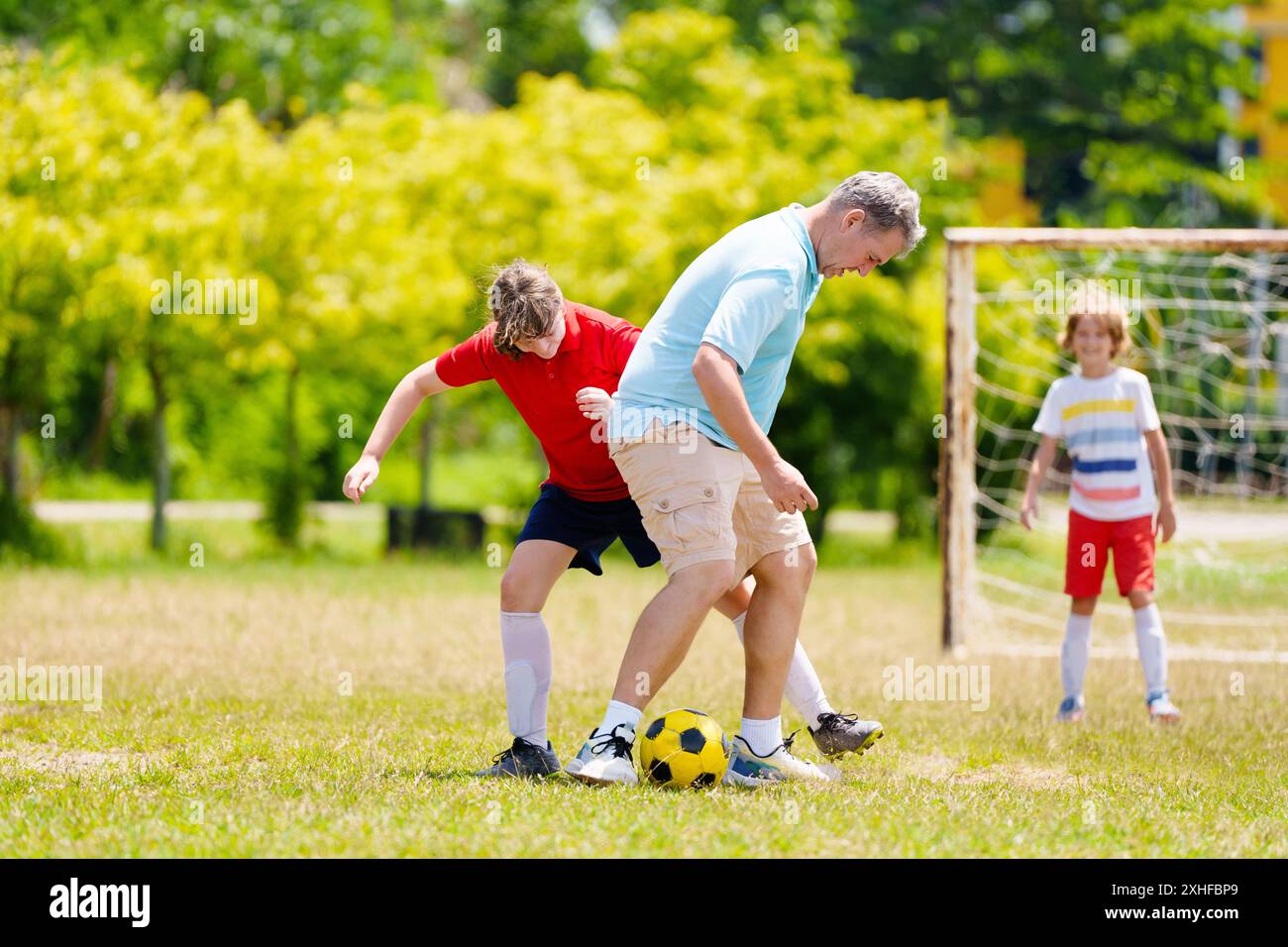 Family playing football. Kids play soccer on outdoor pitch. Little boy ...