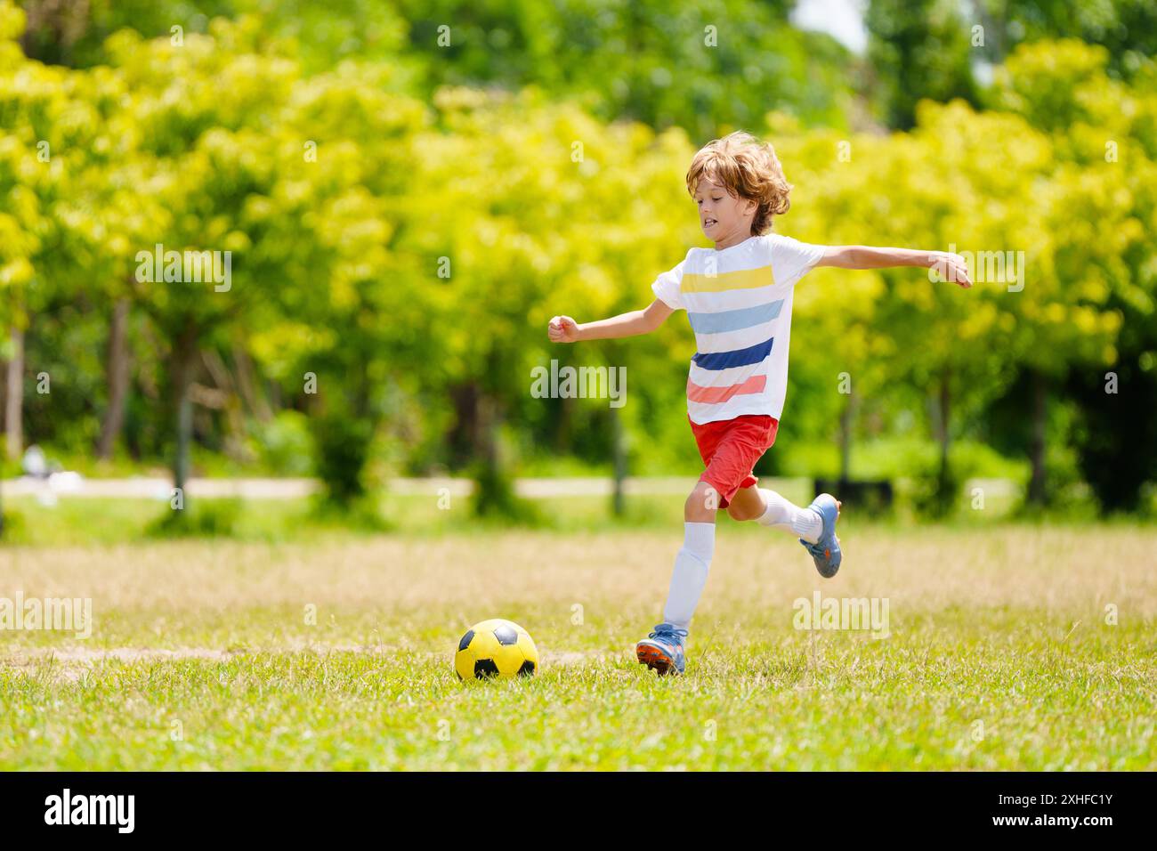 Child playing football. Kids play soccer on outdoor pitch. Little boy ...