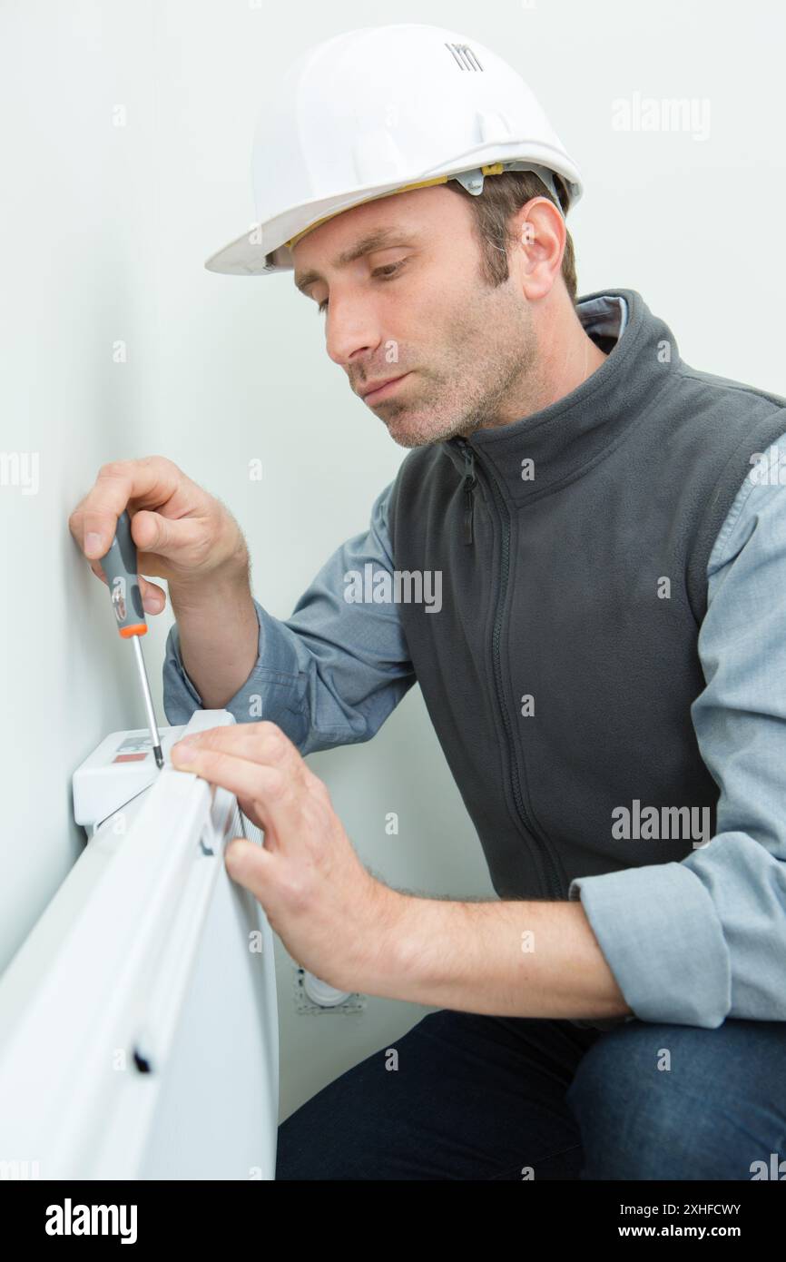 contractor installing electric wall heater Stock Photo - Alamy