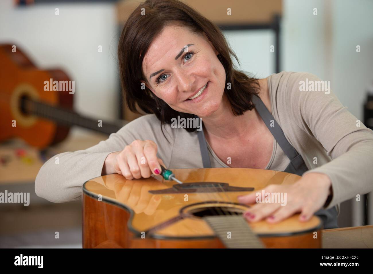 female guitar maker builds string tensioner on new guitar Stock Photo ...