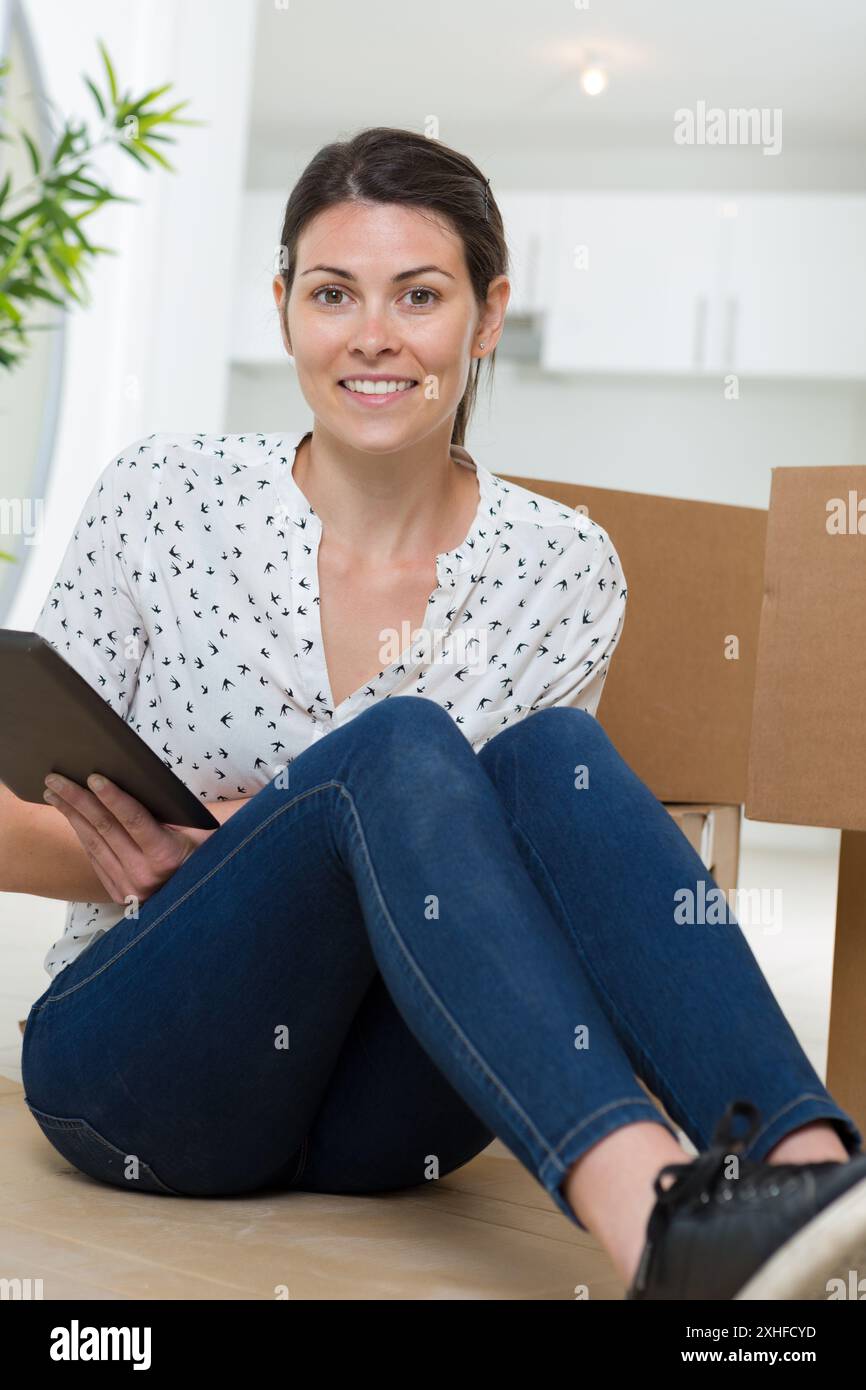 young woman moving house with cardboard boxes and tablet Stock Photo ...