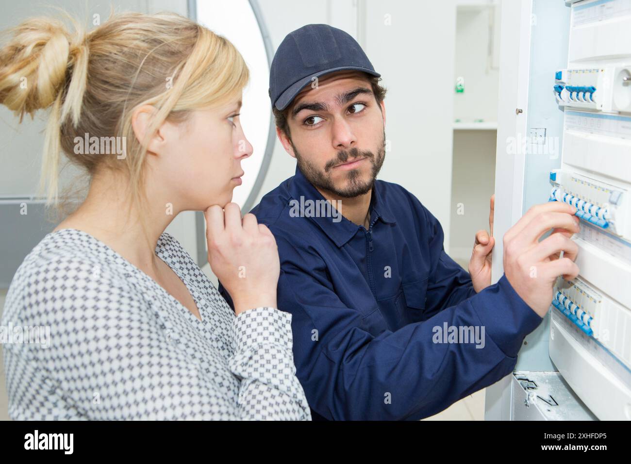 electrician with customer analysing problem in circuit breaker box ...