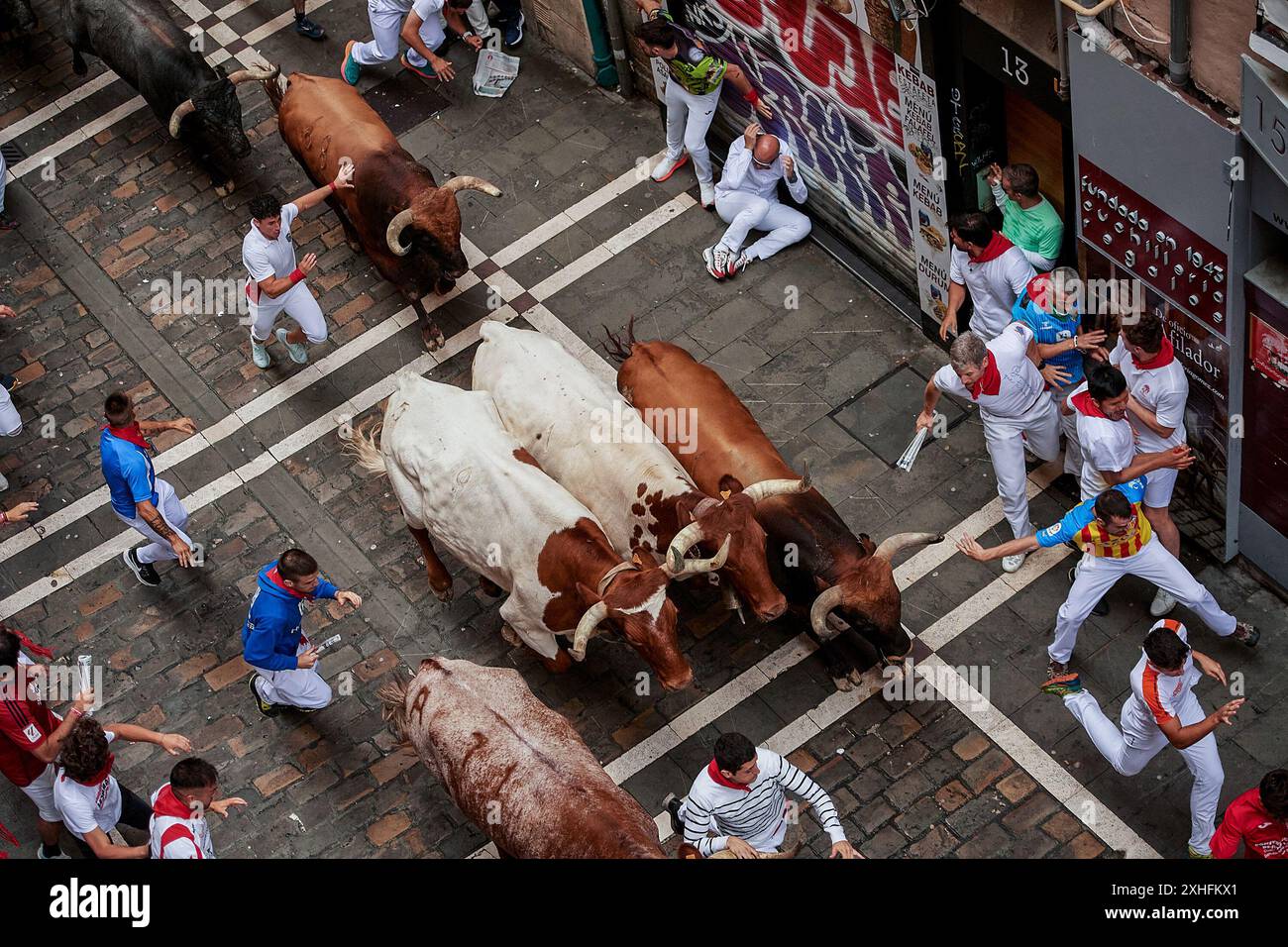 Several young men run in front of the bulls during the running of the ...