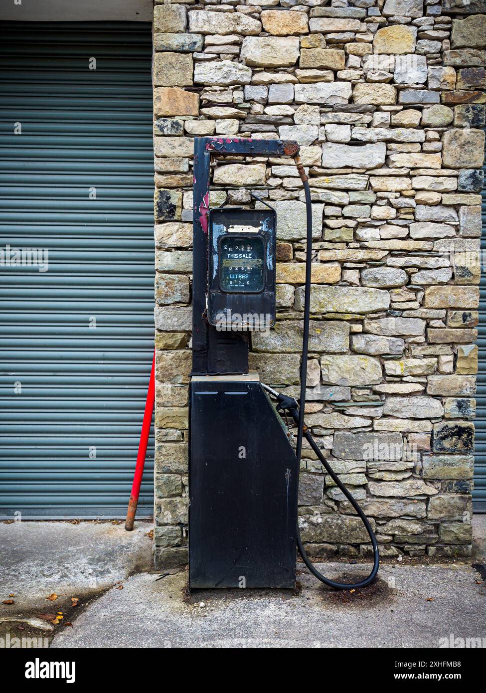 Arnside Cumbria UK. Rustic vintage gas pump beside a textured stone ...
