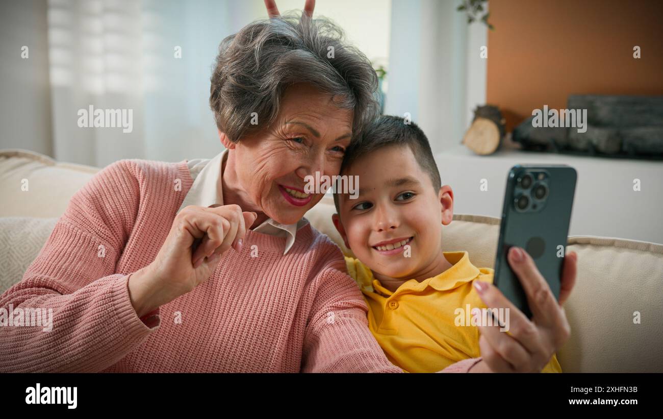 Caucasian grandmother and grandson together at home couch photographed ...