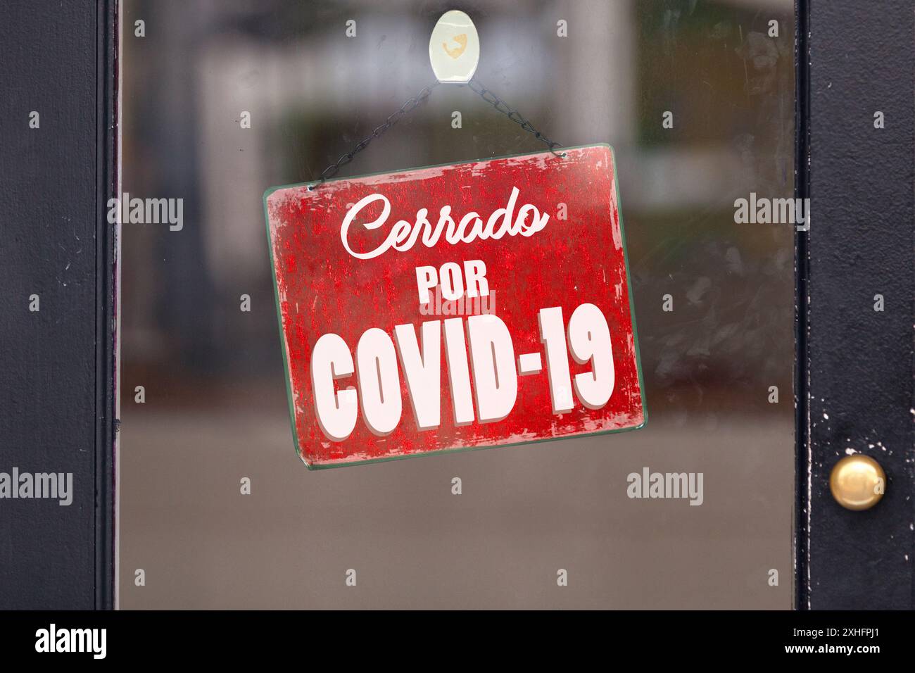 Red closed sign with written in it in Spanish "Cerrado por Covid-19 ...