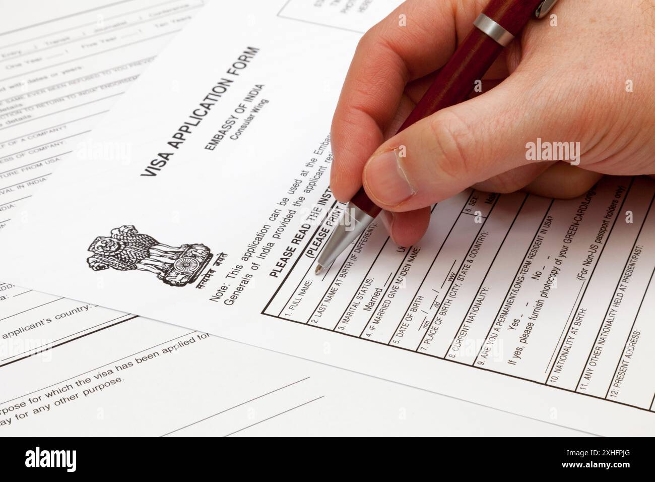 Ballpoint pen hold by the fingers of a man ready to fill a visa ...