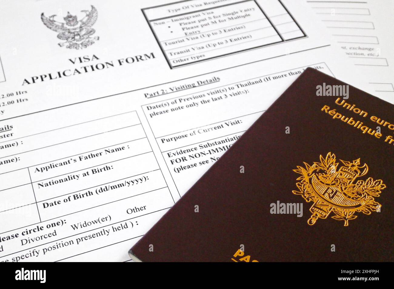 French passport on top of a visa application form to travel to Thailand ...