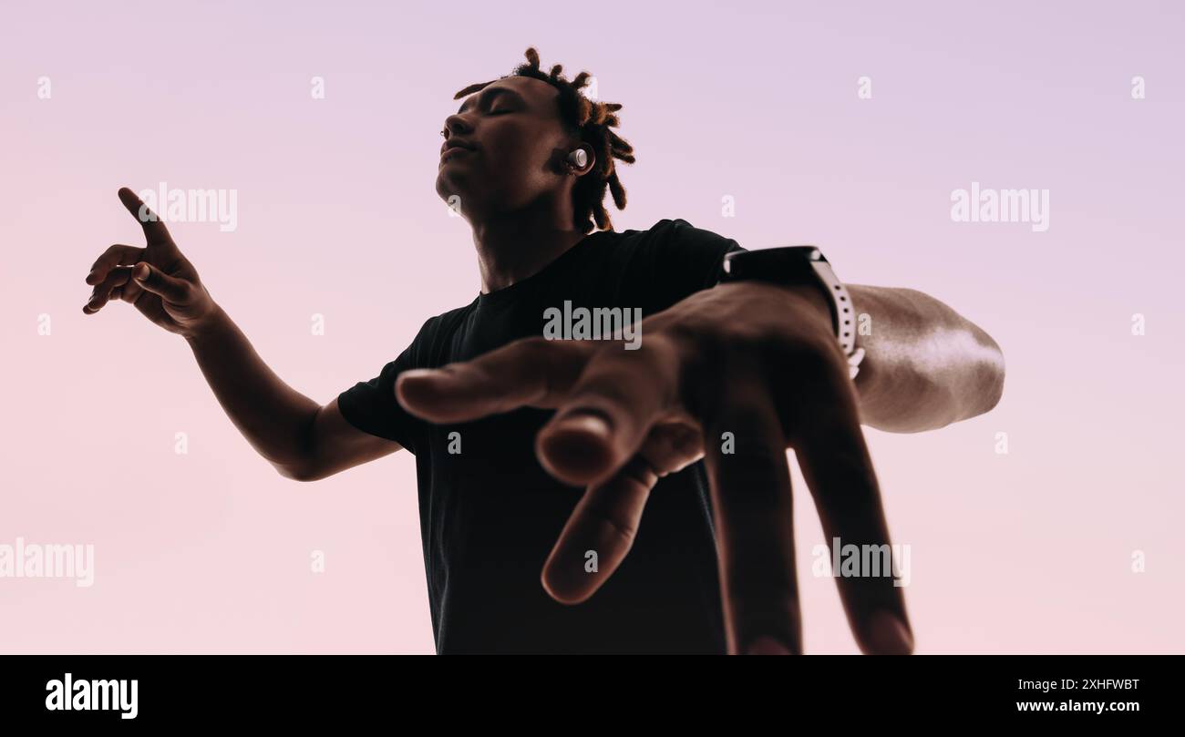 Gen Z man with dreadlocks energetically dances in a studio. Eyes closed ...