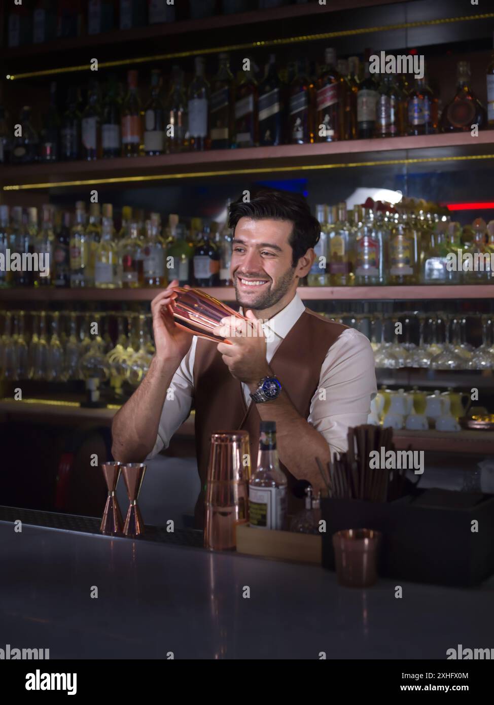 Bartender is making cocktail with talking customer at bar counter Stock ...