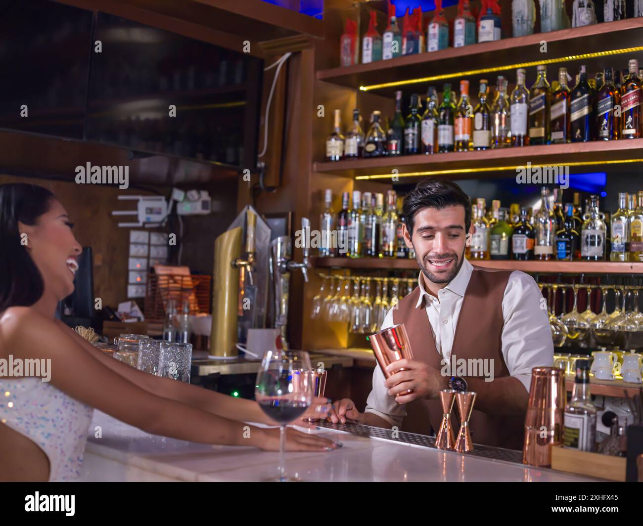 Bartender is making cocktail with talking customer at bar counter Stock ...