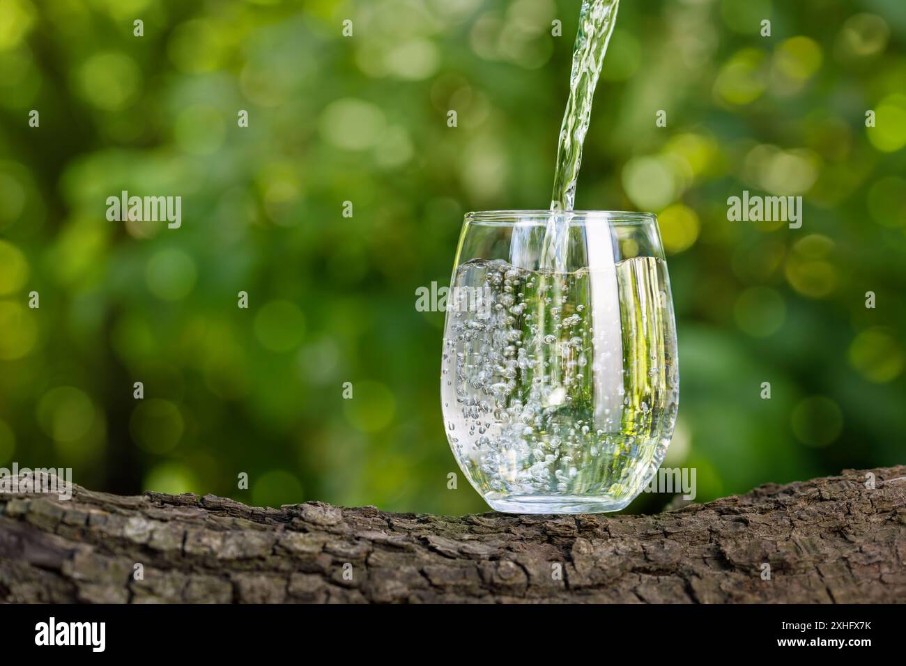 water pouring into glass on log with green natural background Stock ...
