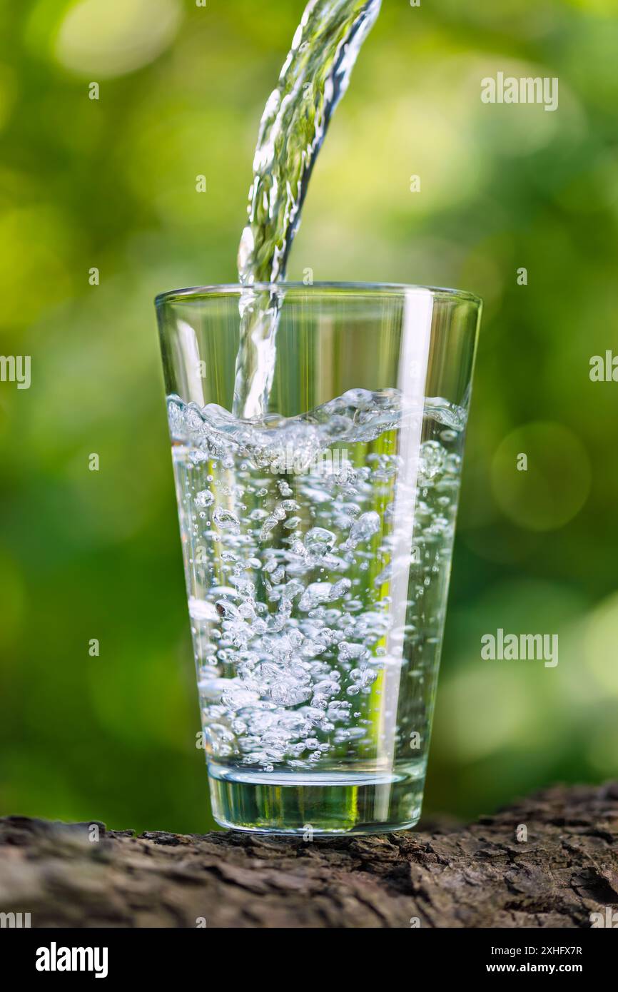 water pouring into glass on log with green natural background Stock ...