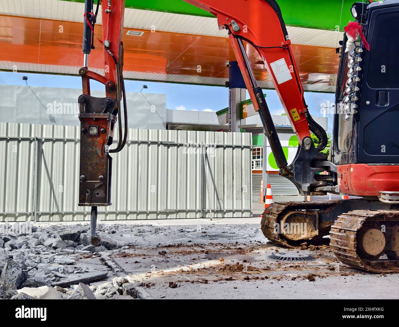 Excavator using hydraulic hammer for breaking concrete at a ...