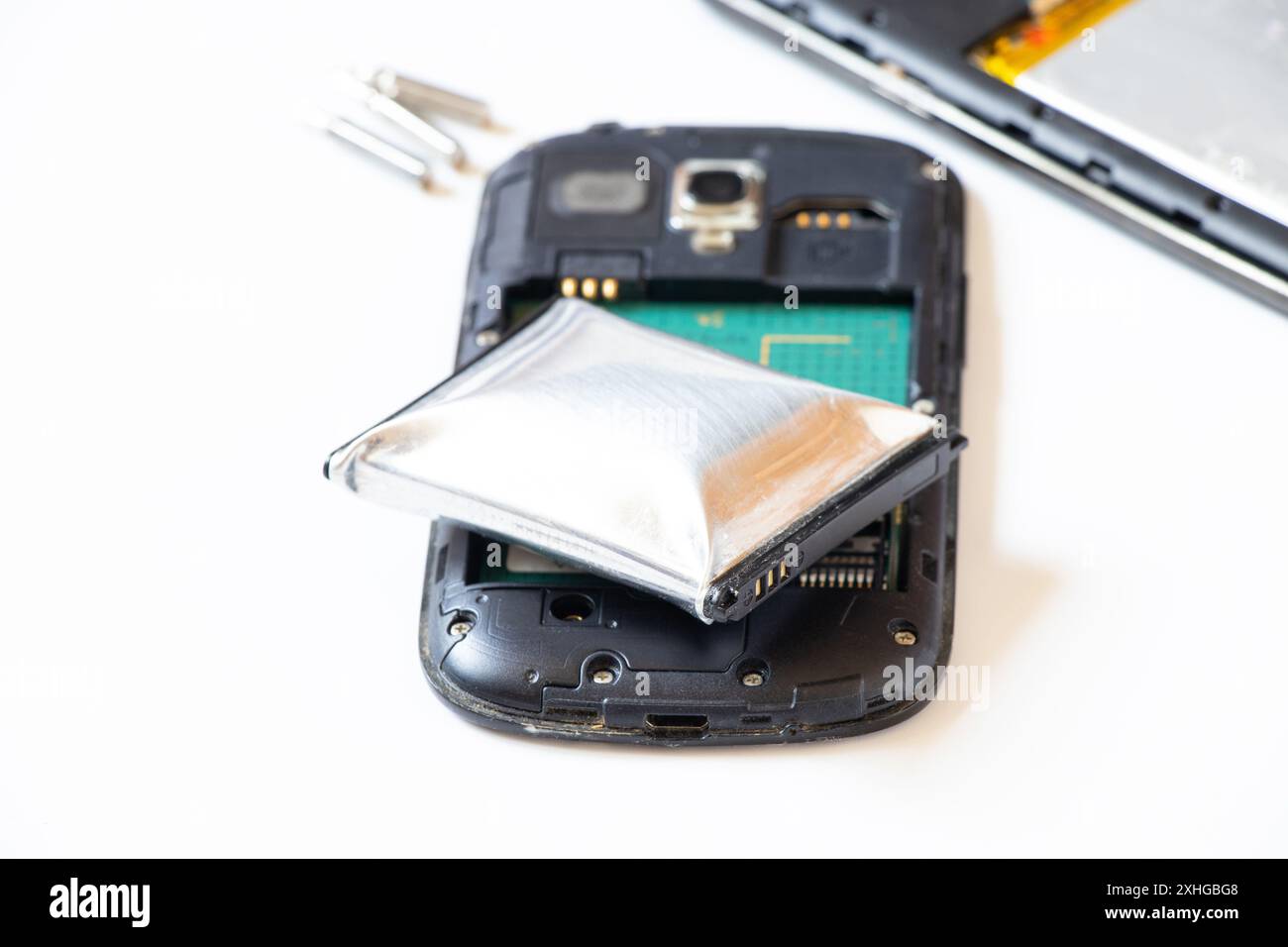 A telephone battery swollen from overheating and a disassembled phone ...