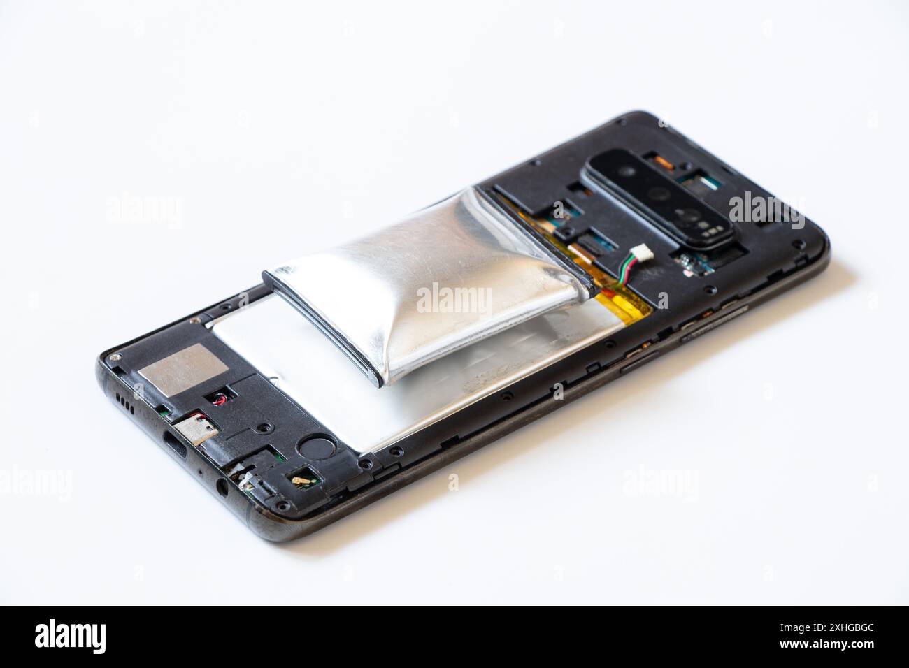 A telephone battery swollen from overheating and a disassembled phone ...