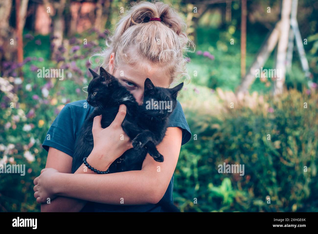 blond girl holding 2 black cats in the garden Stock Photo - Alamy