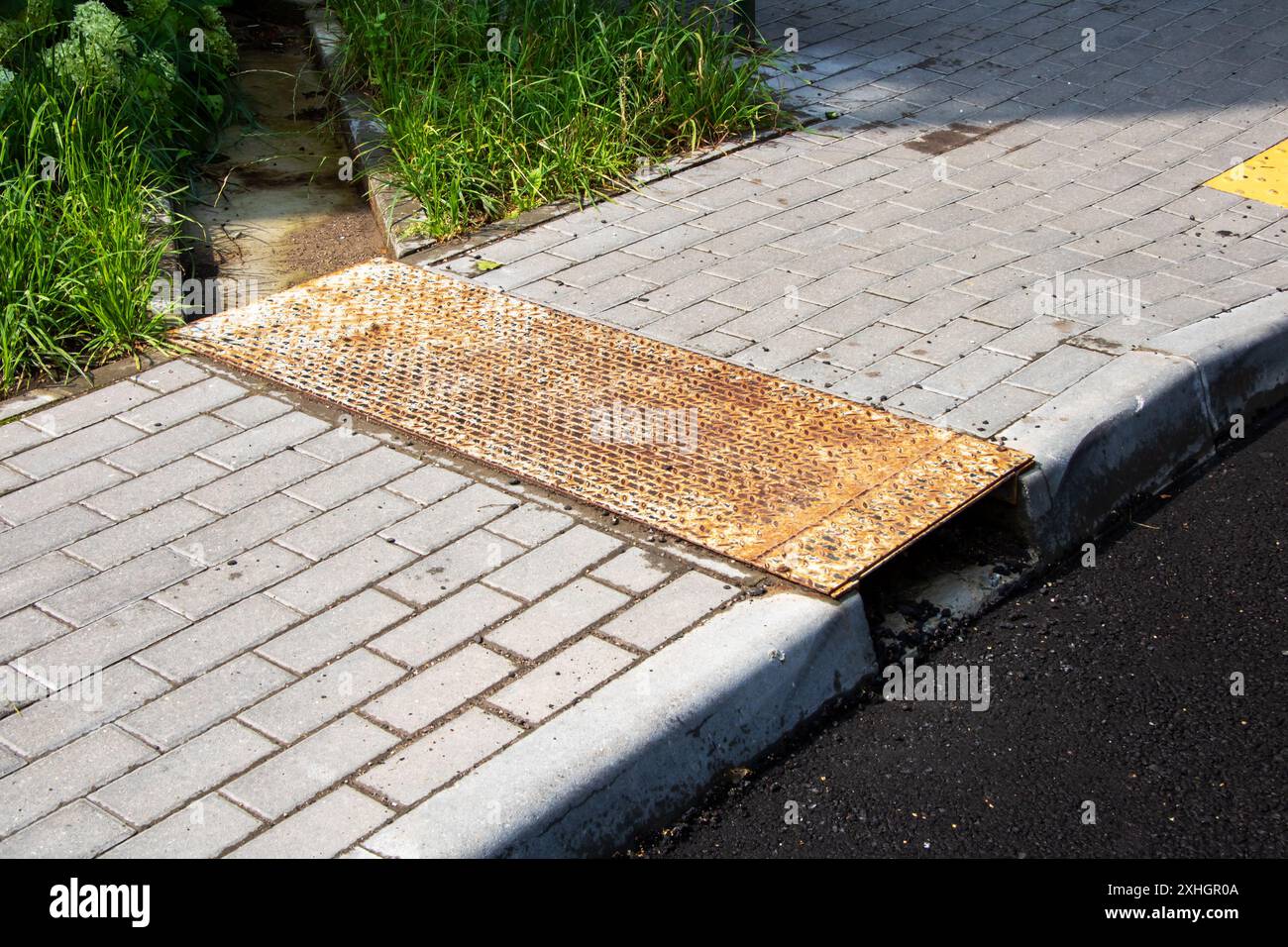 On the brick sidewalk, there is a rusty metal drain cover Stock Photo ...