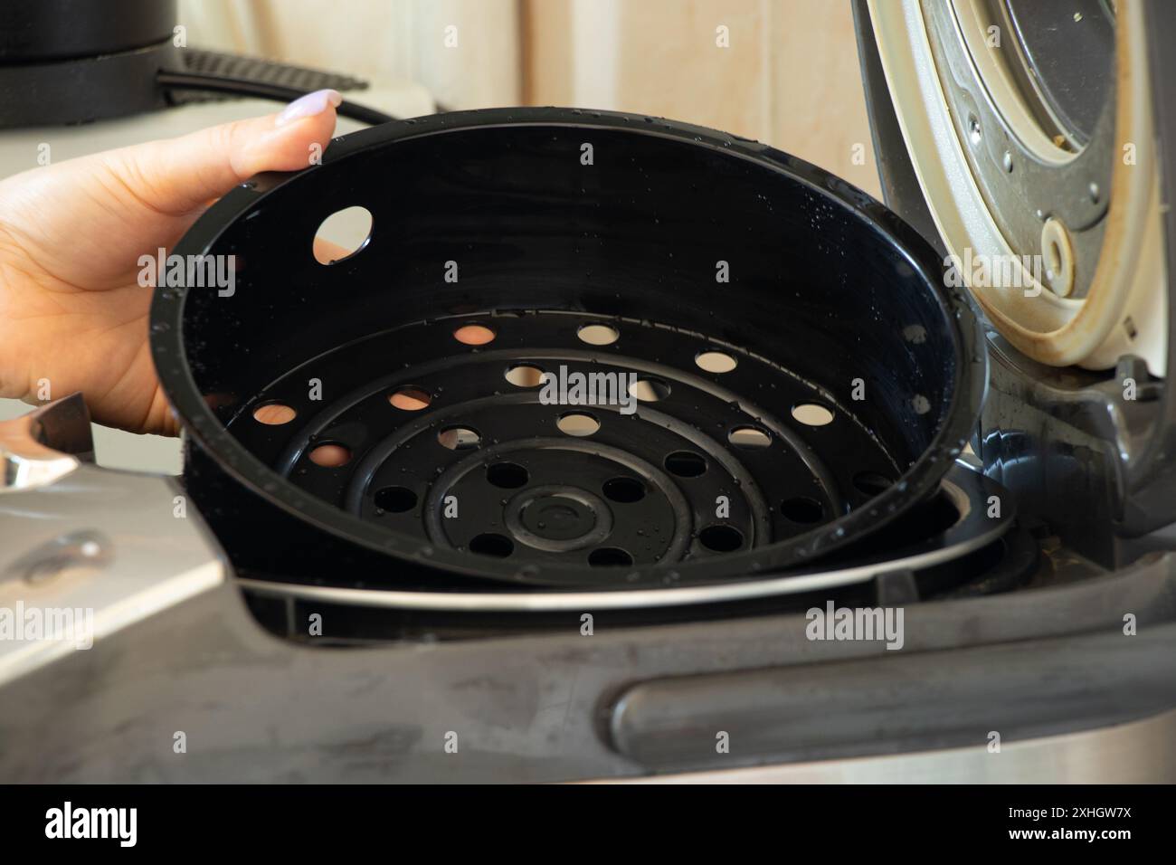 A girl holds in her hand a container for steaming for a multi cooker in ...