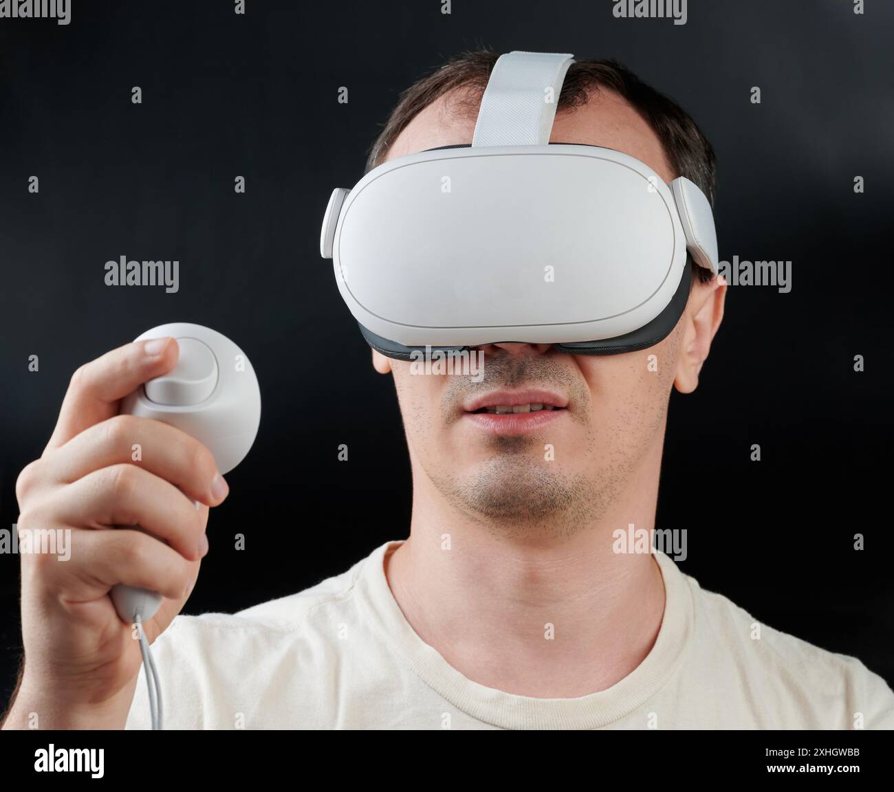 Man in white VR headset front view isolated on black studio background ...