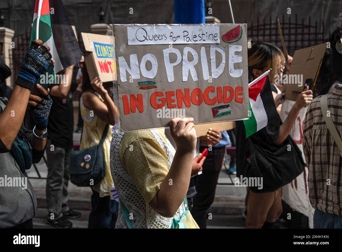 A non-binary supporter holds a placard saying "No Pride In Genocide ...
