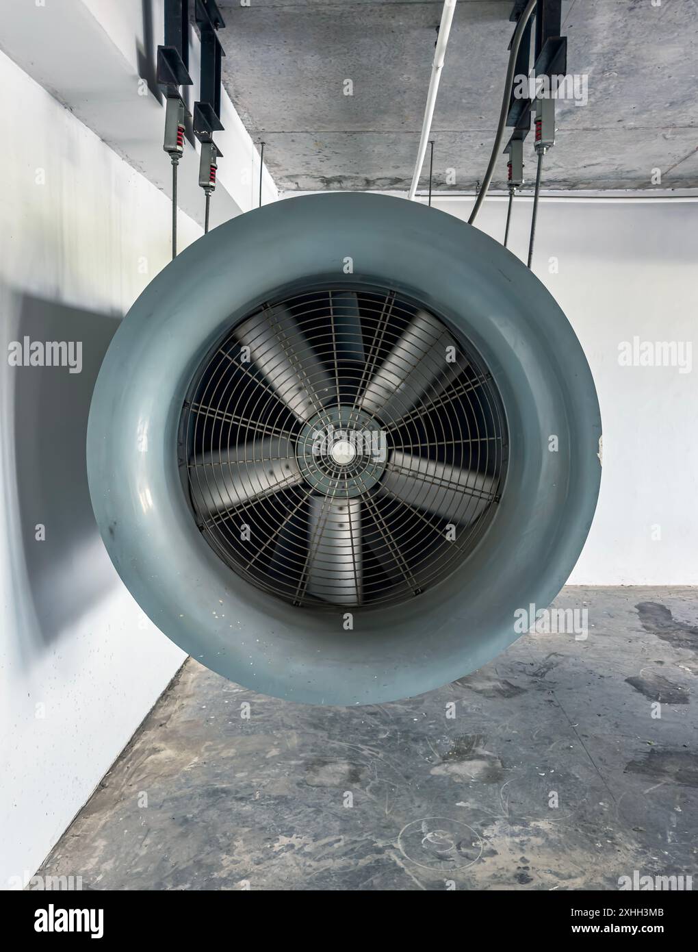 A large, gray, industrial fan is suspended from the ceiling of a ...