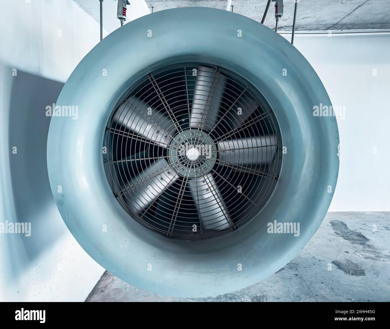 A large, gray, industrial fan is suspended from the ceiling of a ...