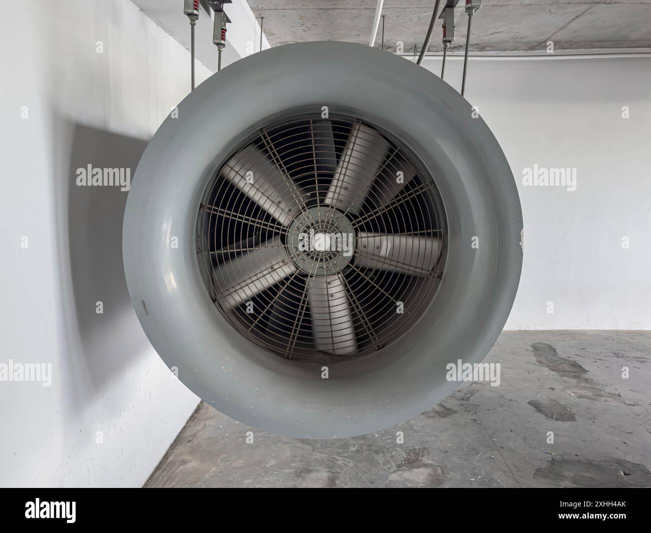 A large, gray, industrial fan is suspended from the ceiling of a ...