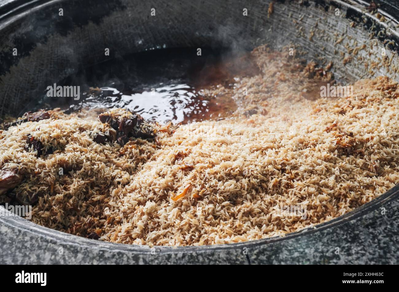 oriental dish of Uzbek cuisine is rice pilaf with meat lamb in cauldron ...