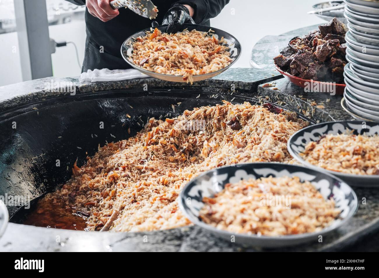 hands of a male chef cooking traditional oriental Arabic Uzbek rice ...