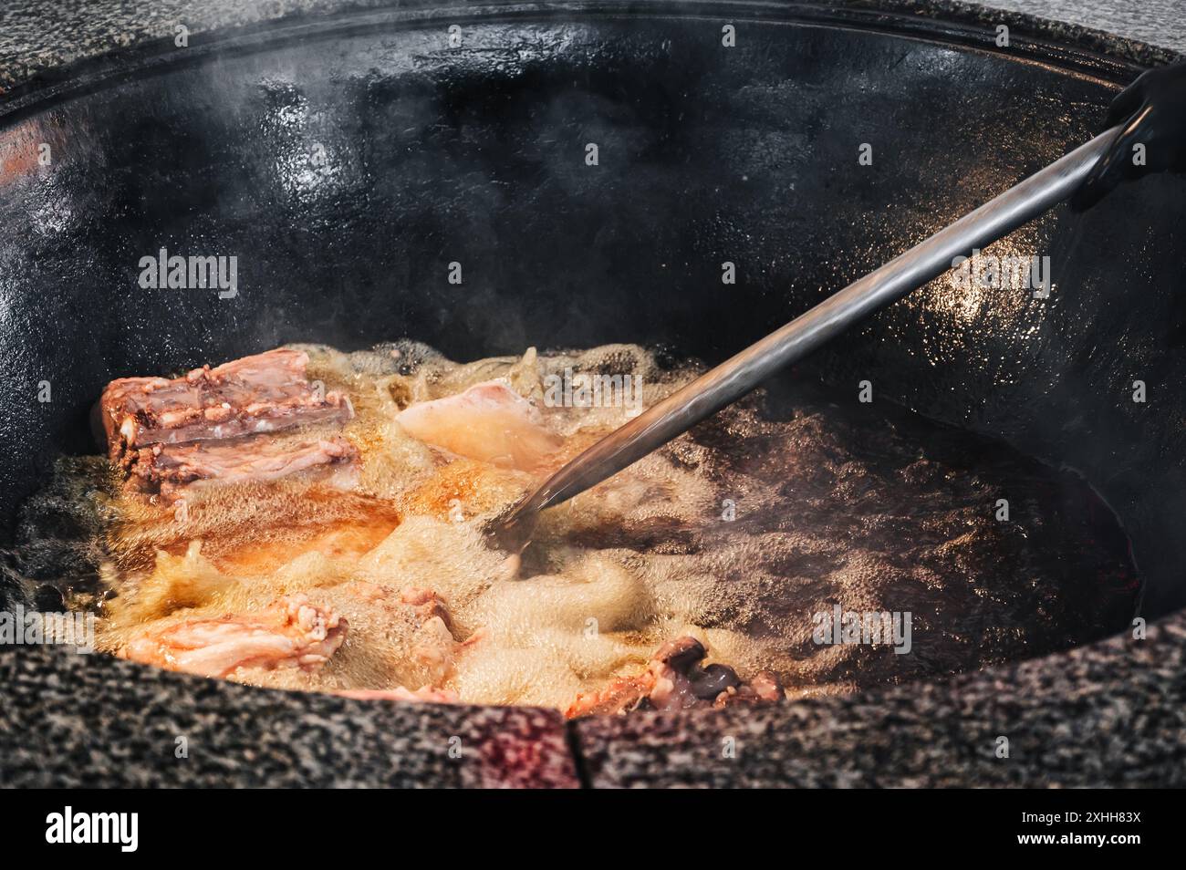 chef cooks lamb meat in a boiling cauldron for traditional oriental ...