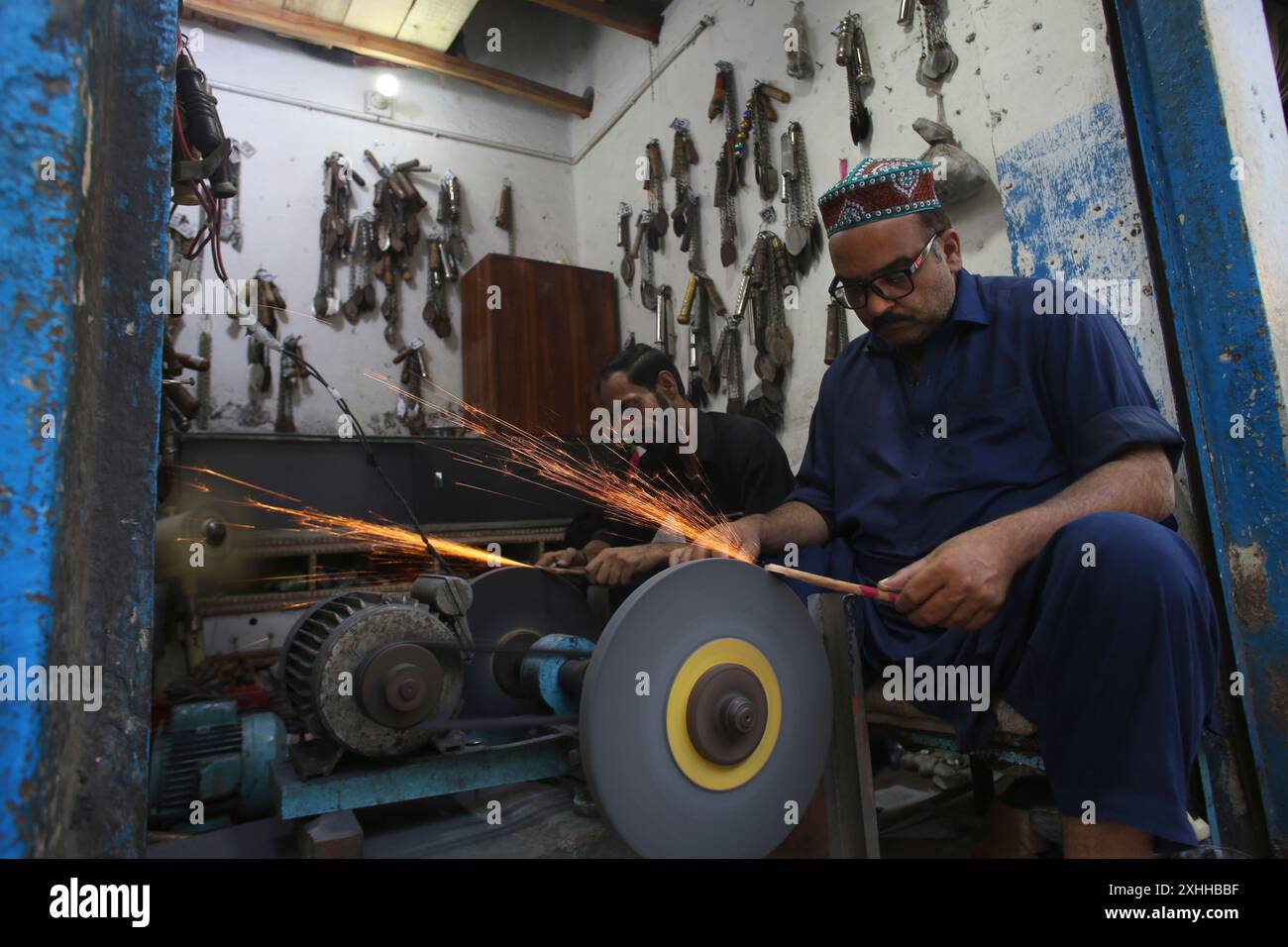 Pakistani iron smiths sharpens knives, as bunches of knives and chains ...
