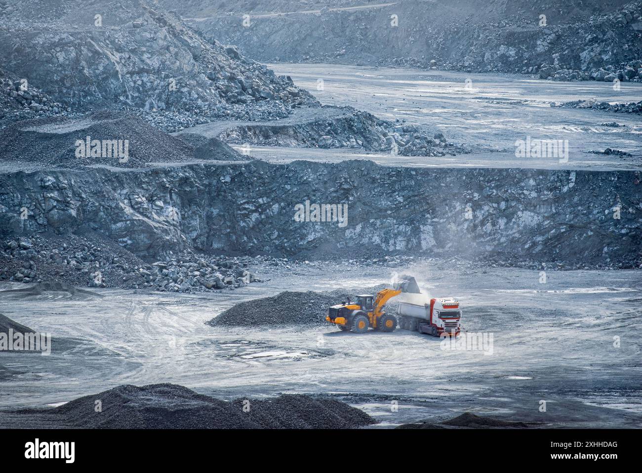 Loader filling a dump truck in diabase quarry with rocky terrain ...
