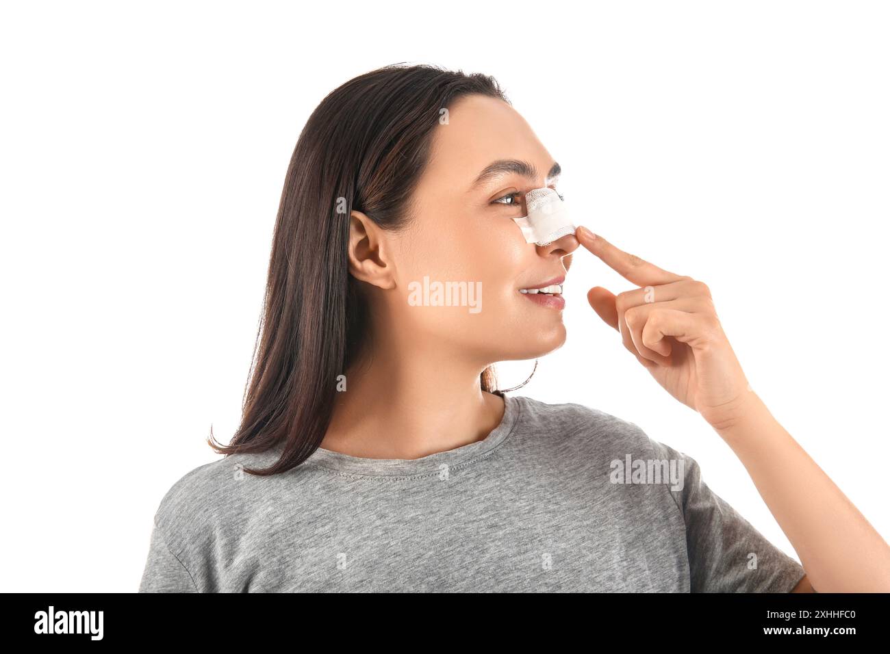 Young woman pointing at bandaged nose on white background. Plastic ...