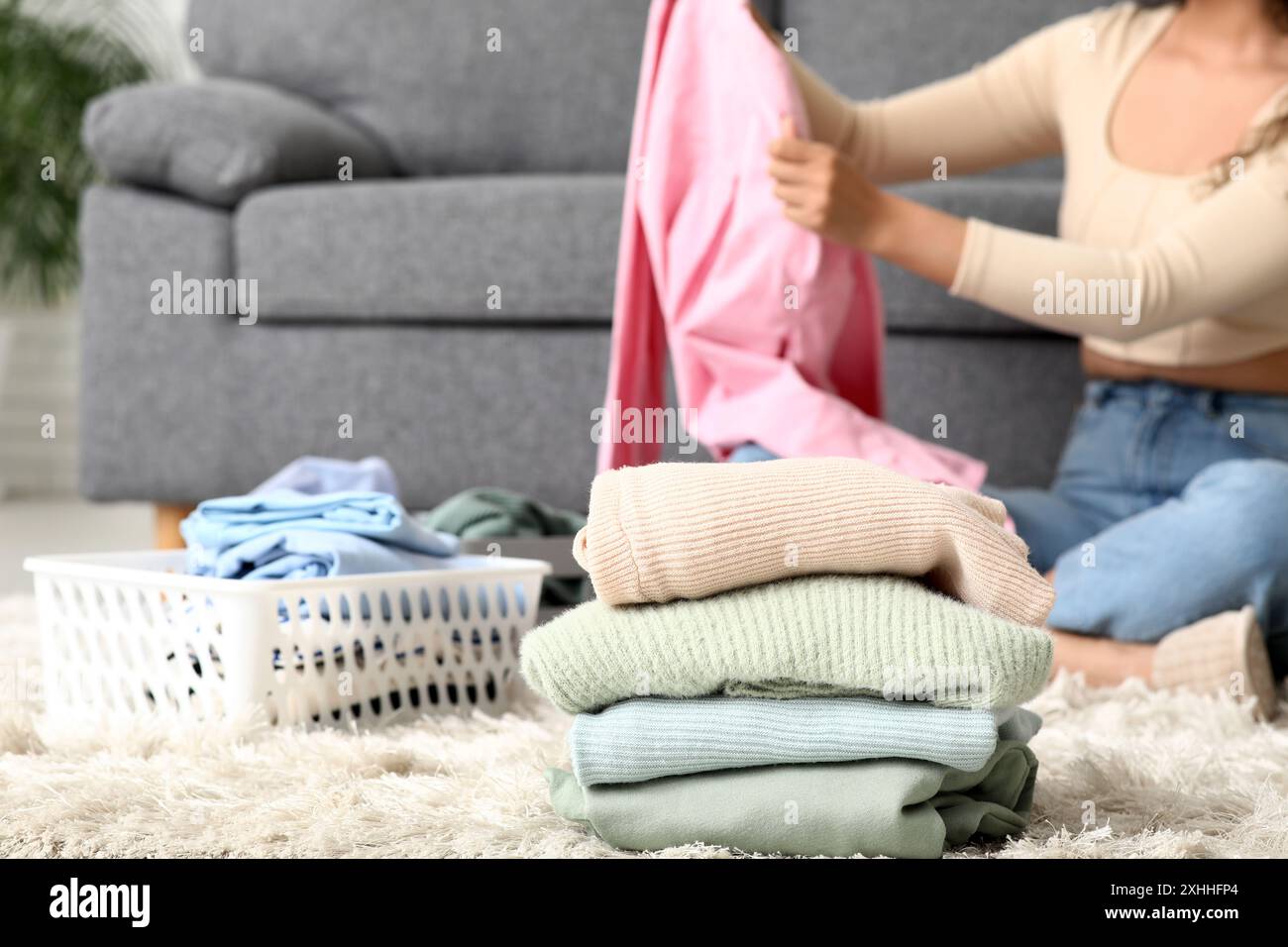 Beautiful young African-American woman folding clean clothes at home ...