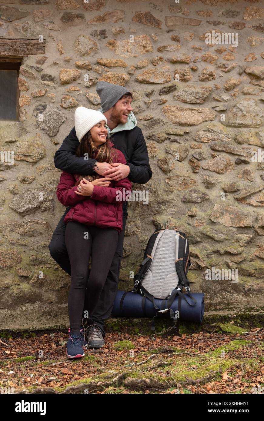 couple of young mountaineers hugging leaning on a shelter wall in the ...