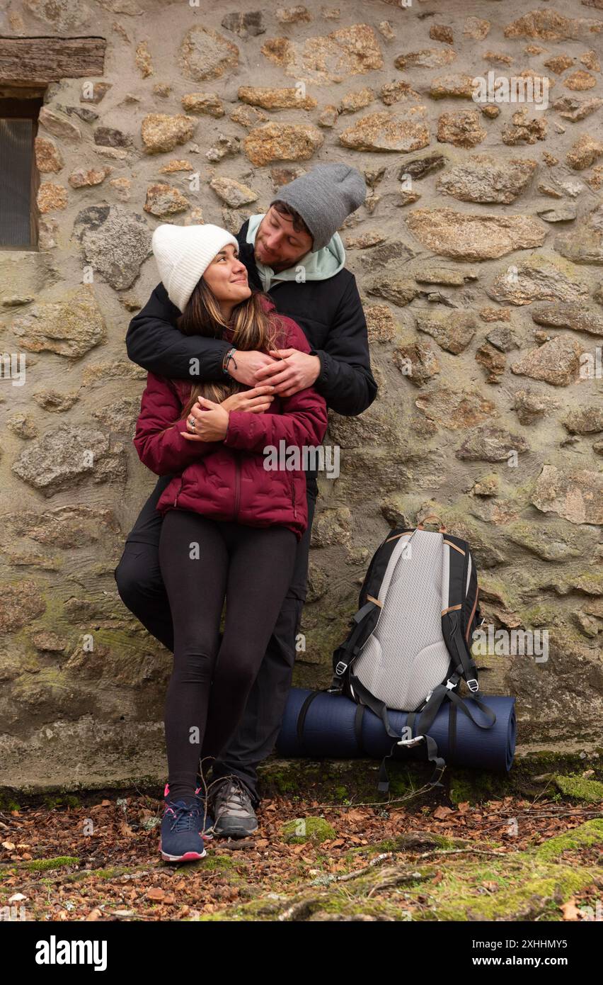 couple of young mountaineers hugging leaning on a shelter wall in the ...