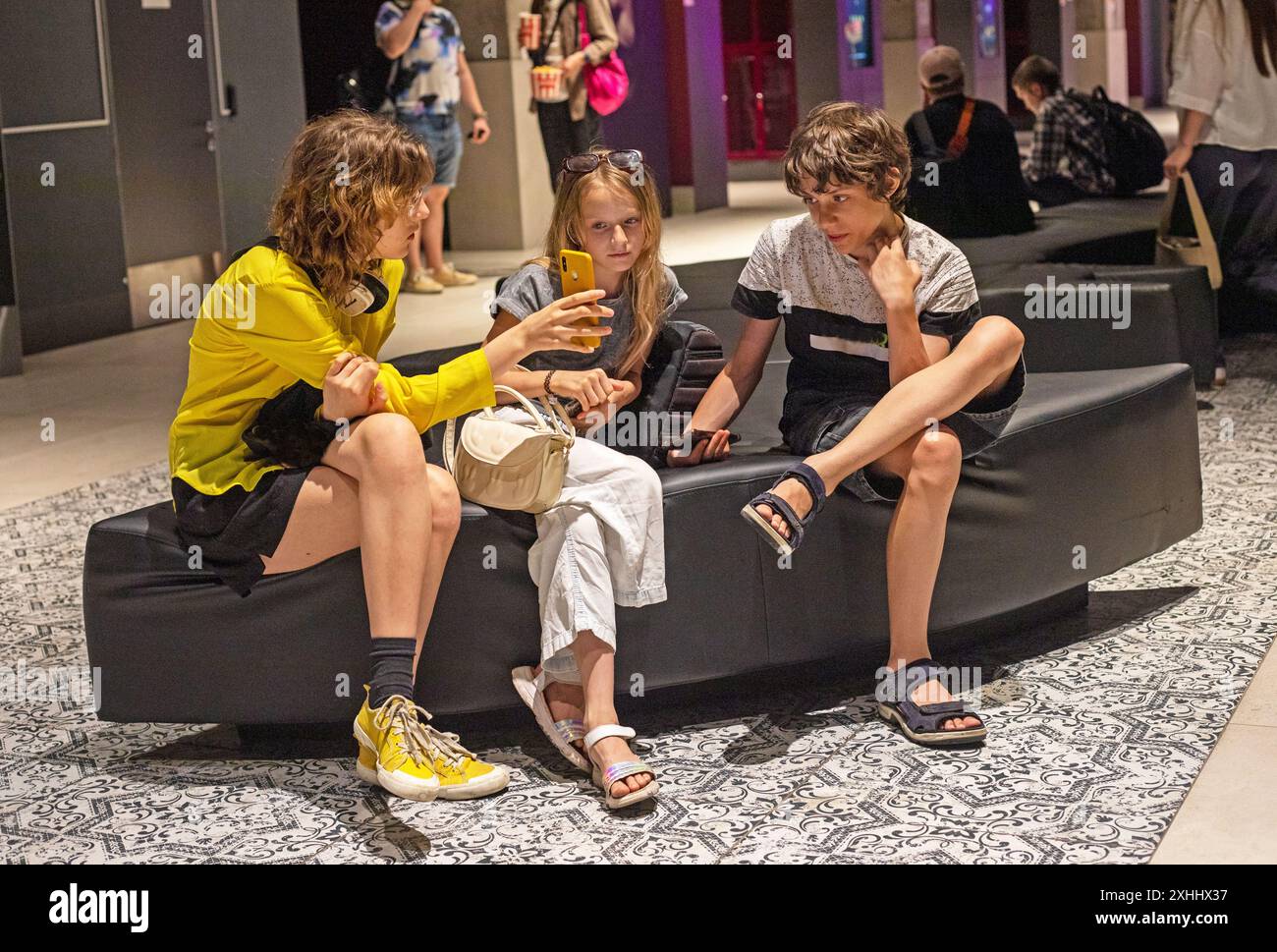 three teenage children chatting in the waiting room before the film ...