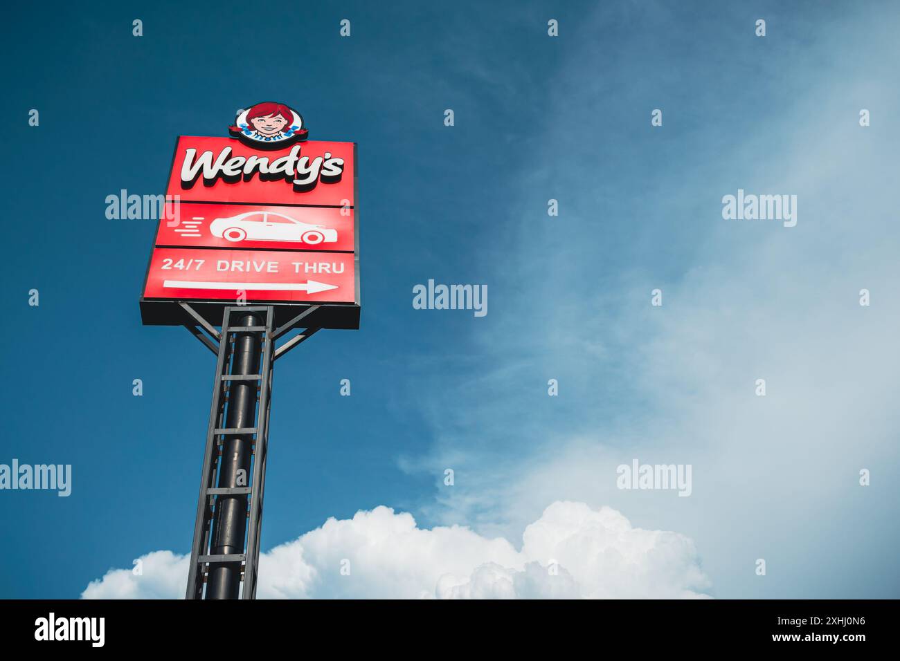 Wendy's drive thru sign standing high against a blue sky background ...