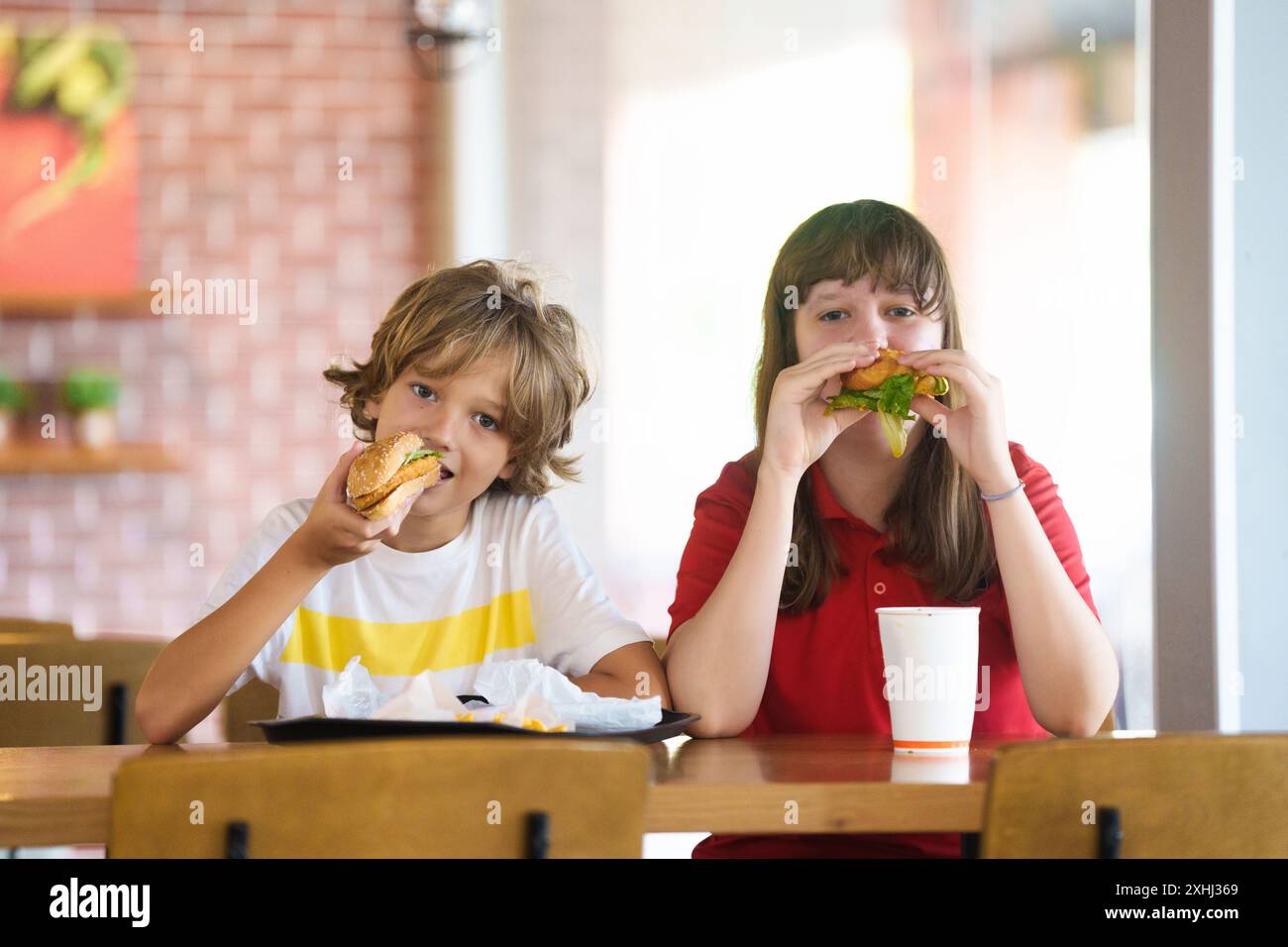Kids eating fastfood. Unhealthy junk food. Children eat burger, chips und chicken nuggets in ...