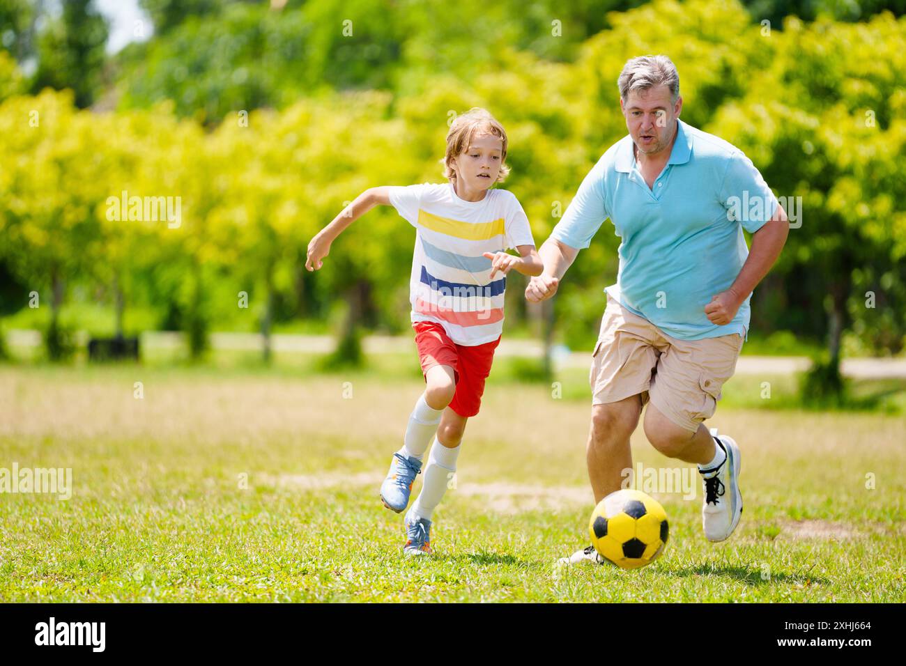 Child playing football. Kids play soccer on outdoor pitch. Little boy ...